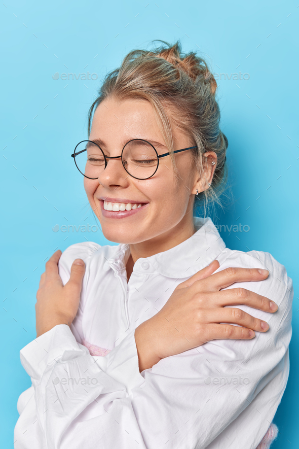 Pleased Sincere Woman Embraces Herself Keeps Arms Crossed Hands On